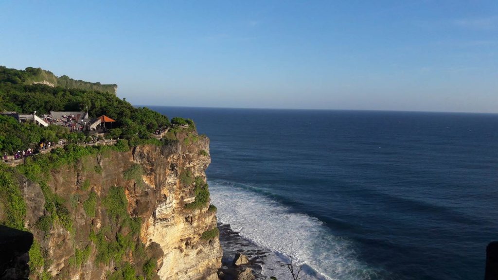 O templo de Uluwatu fica em um penhasco super perto do mar. Foto ...